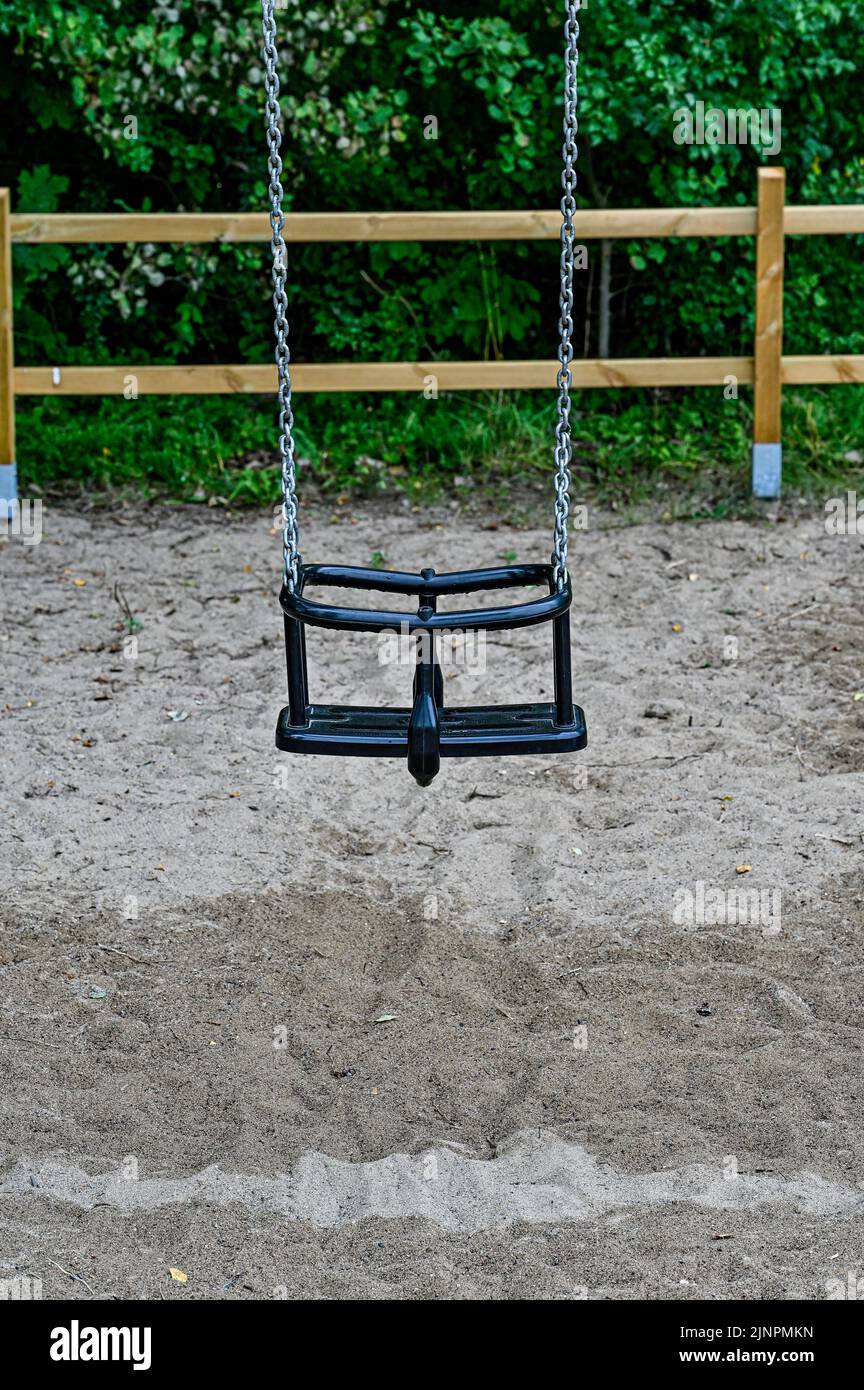 swing in chains at playingground with fence Stock Photo - Alamy