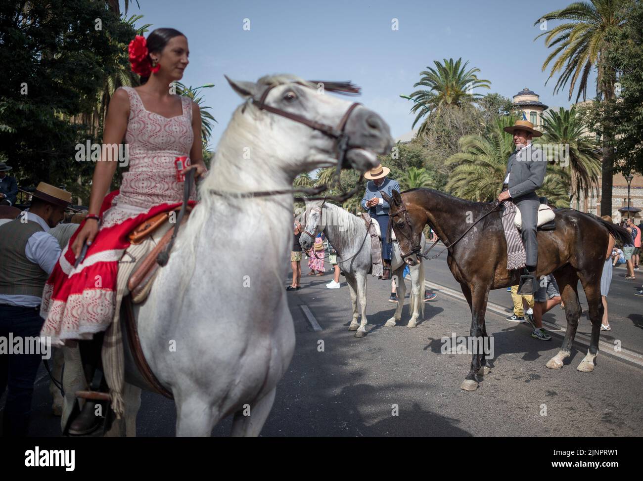 A woman wearing a flamenco dress is seen mounting on a horse as she ...