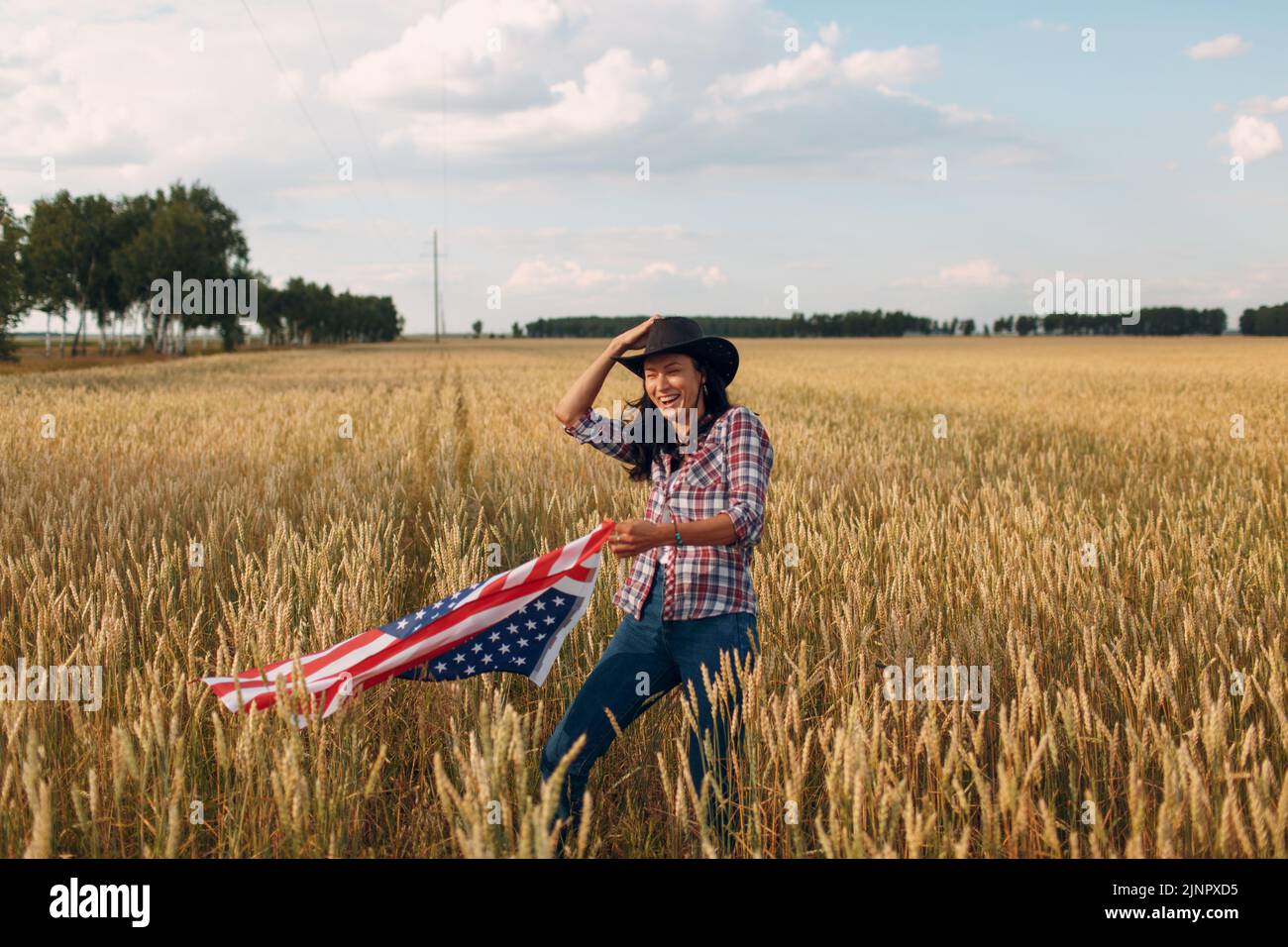 Woman farmer wearing cowboy hat, plaid shirt and jeans with american ...