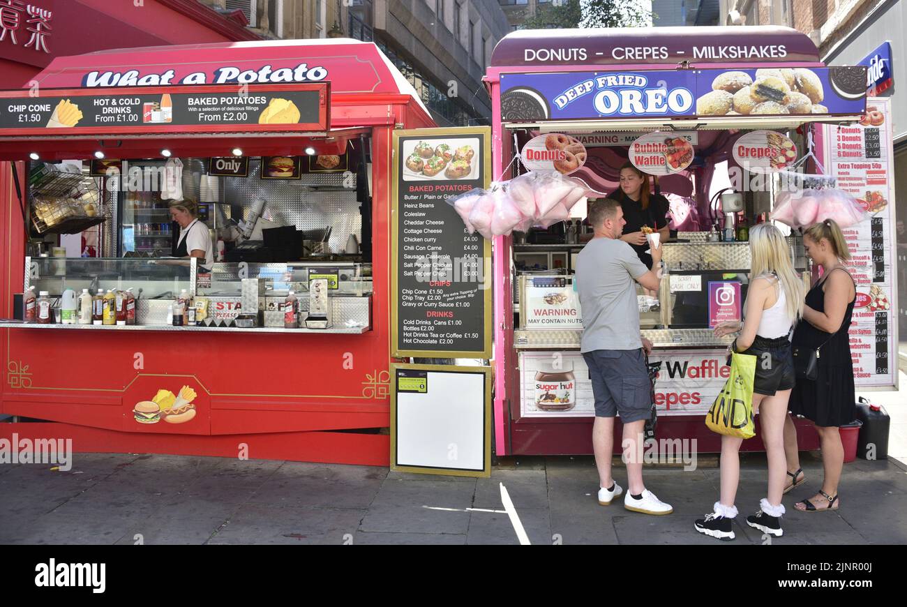 People shop at a crepe, donut and milkshake stall, with another food ...