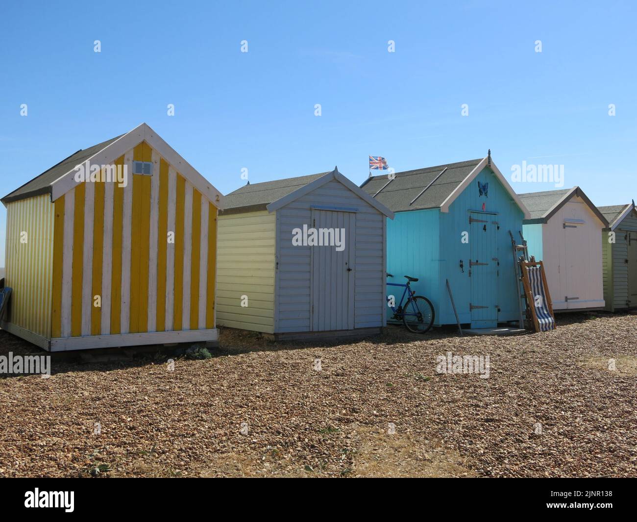 A row of traditional wooden beach huts in English seaside colours on a ...