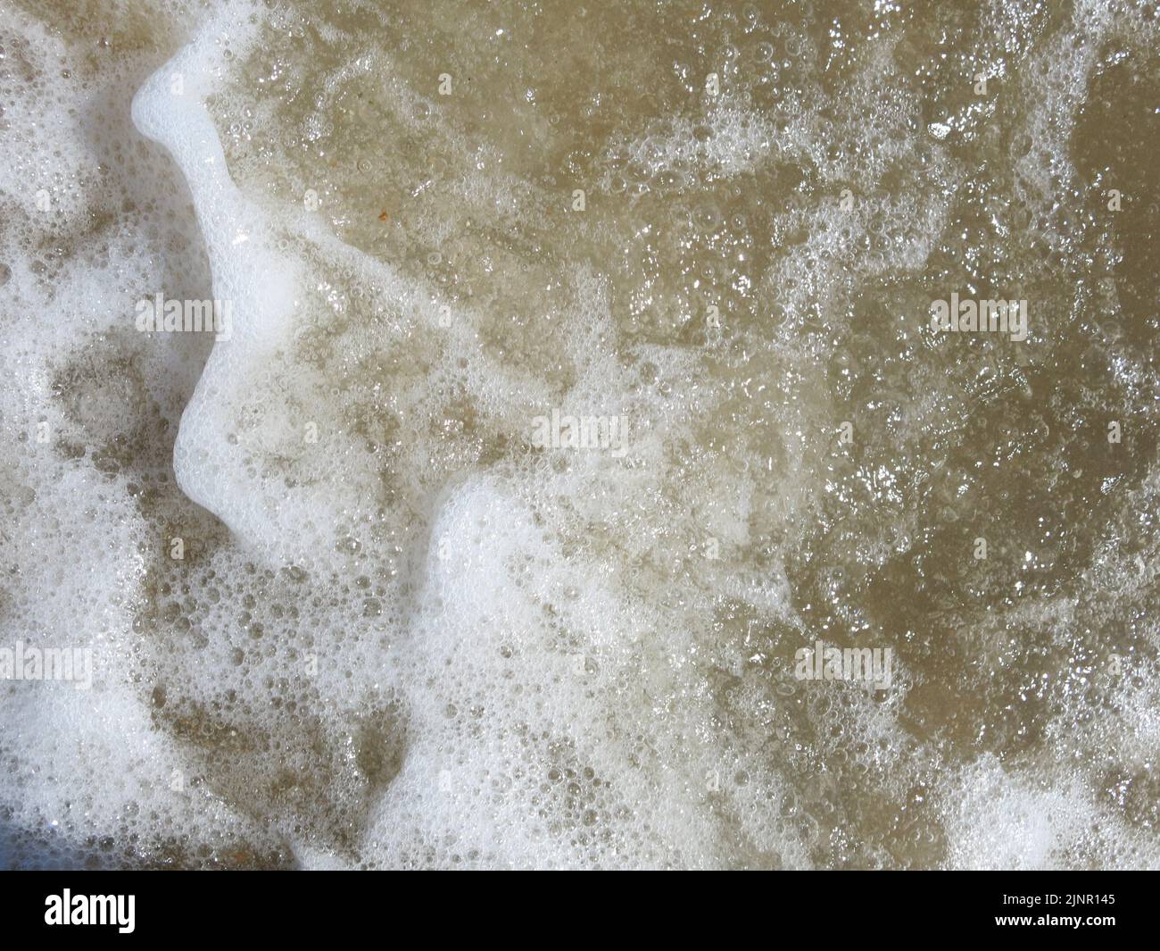 Close-up of the frothy white foam and bubbles from waves lapping the ...