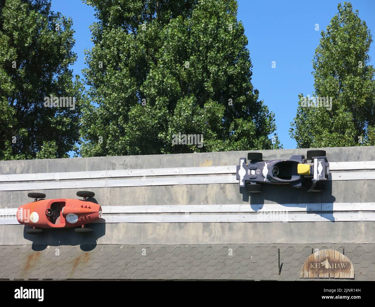 Two model racing cars mounted on a track along a piece of wall at Beach ...