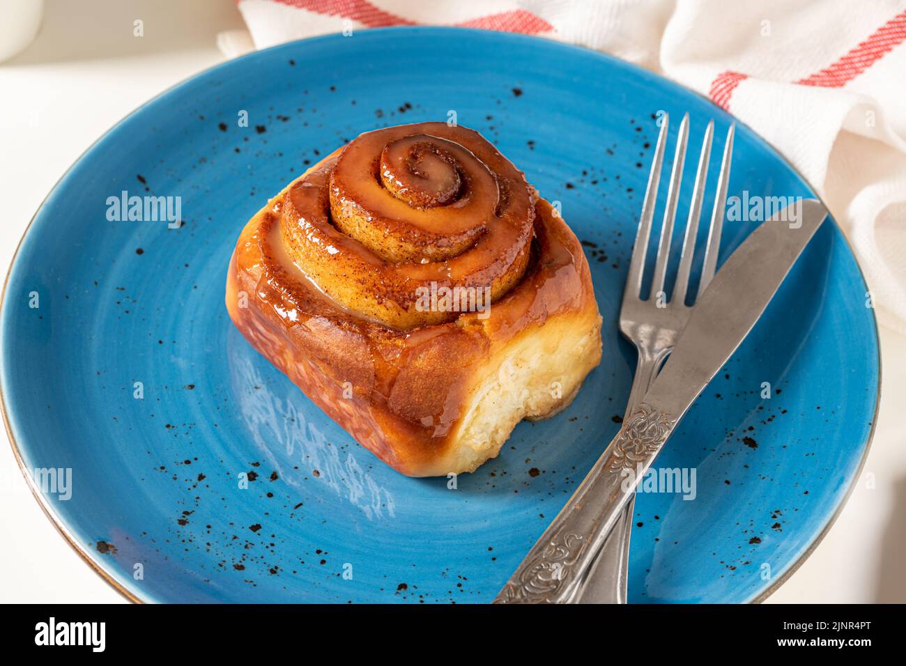 Freshly baked cinnamon roll on a blue porcelain plate Stock Photo - Alamy