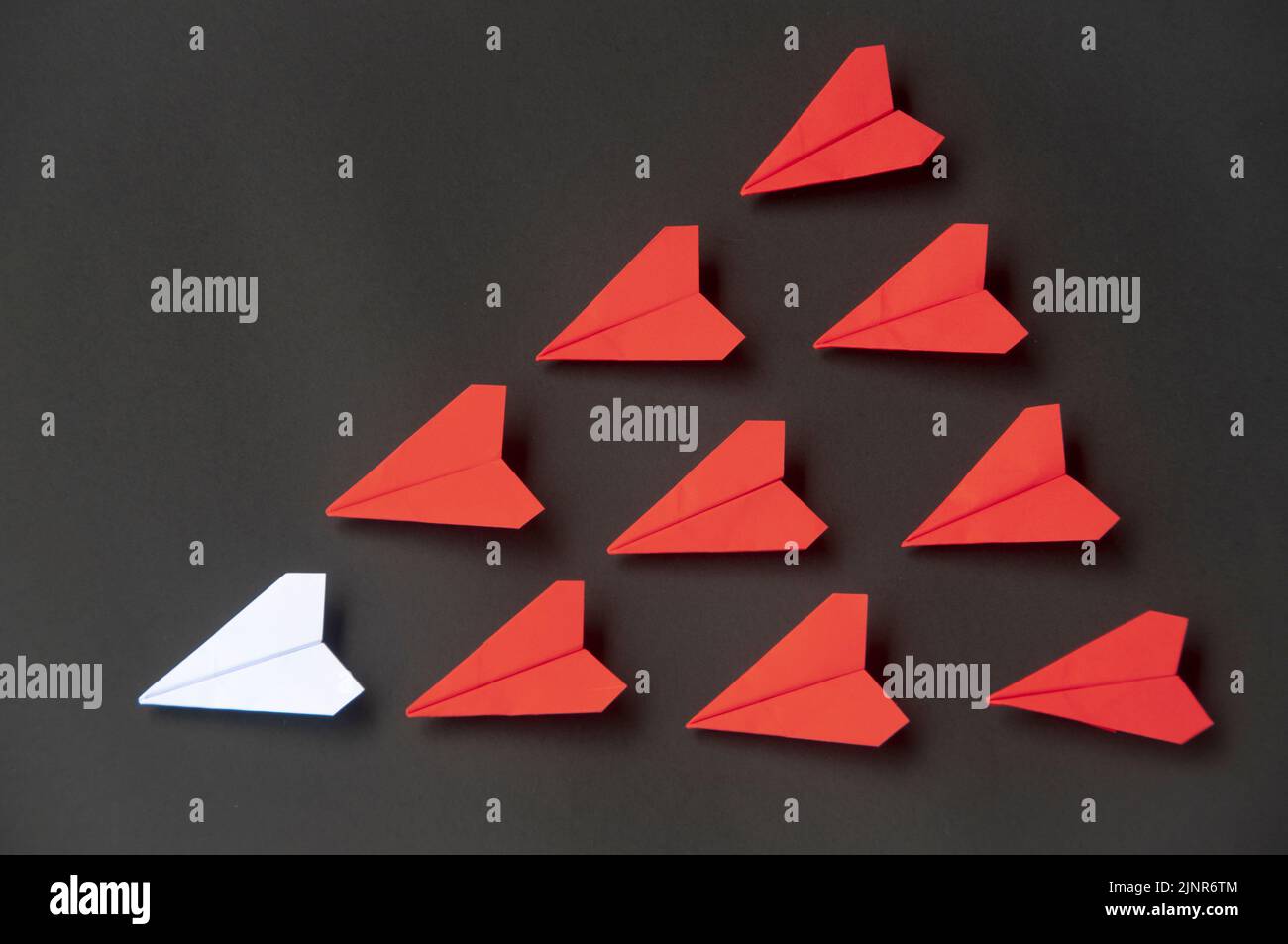 White paper plane origami leading red planes on dark background ...