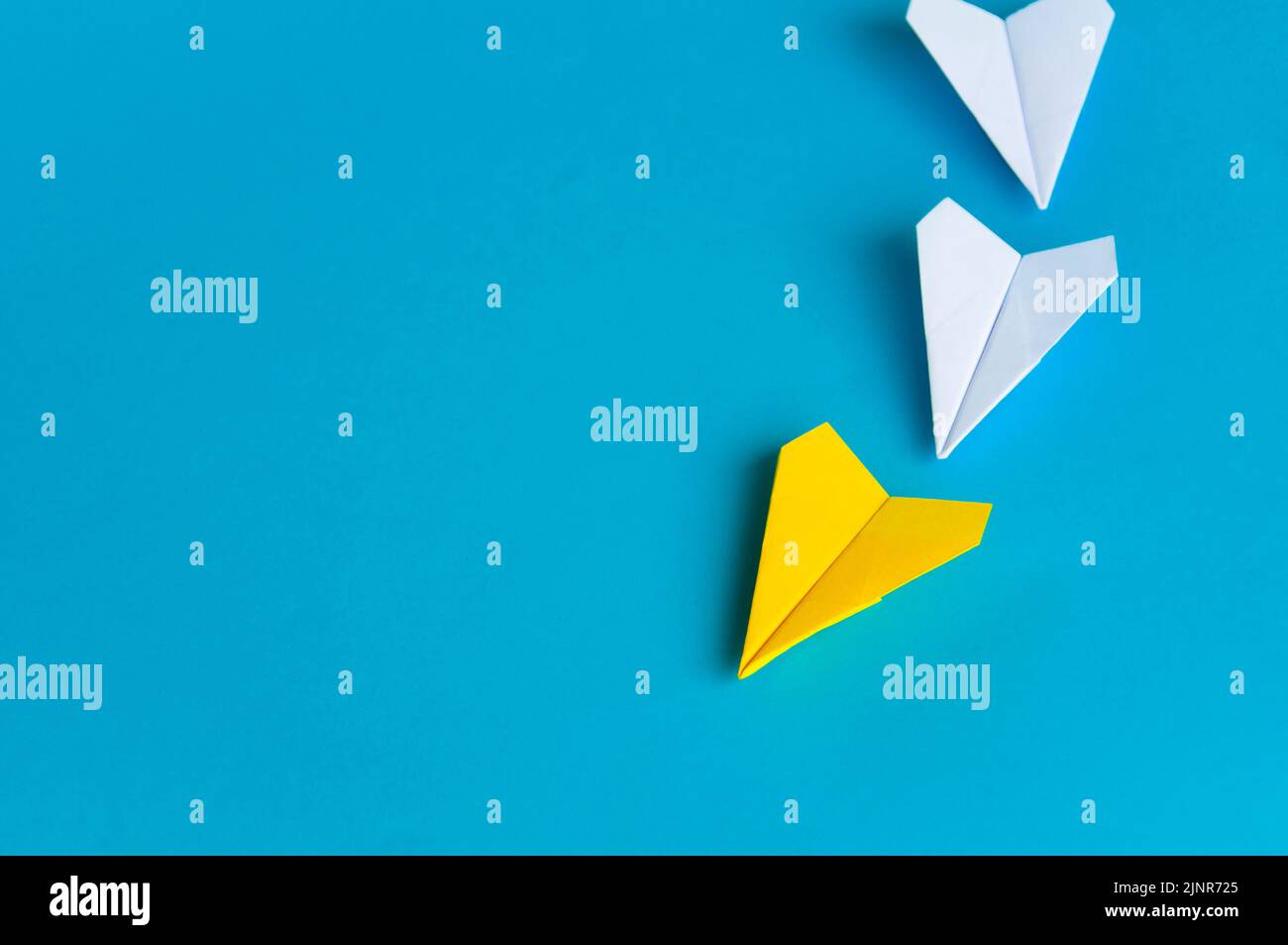 Yellow paper plane origami leading white planes on blue background ...