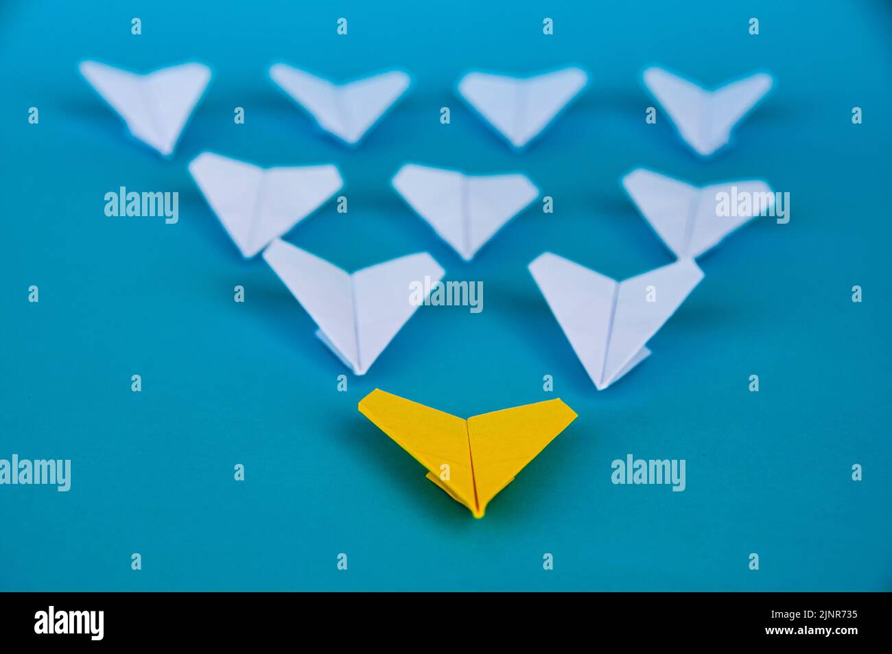 Yellow paper plane origami leading white planes on blue background ...