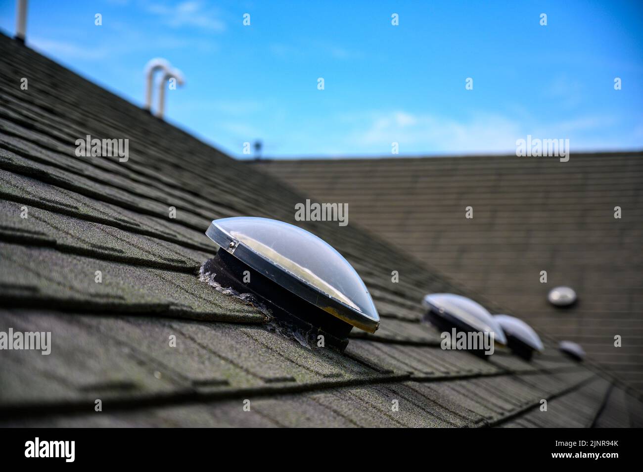 Dome shaped solar tube skylight on asphalt shingle roof Stock Photo - Alamy