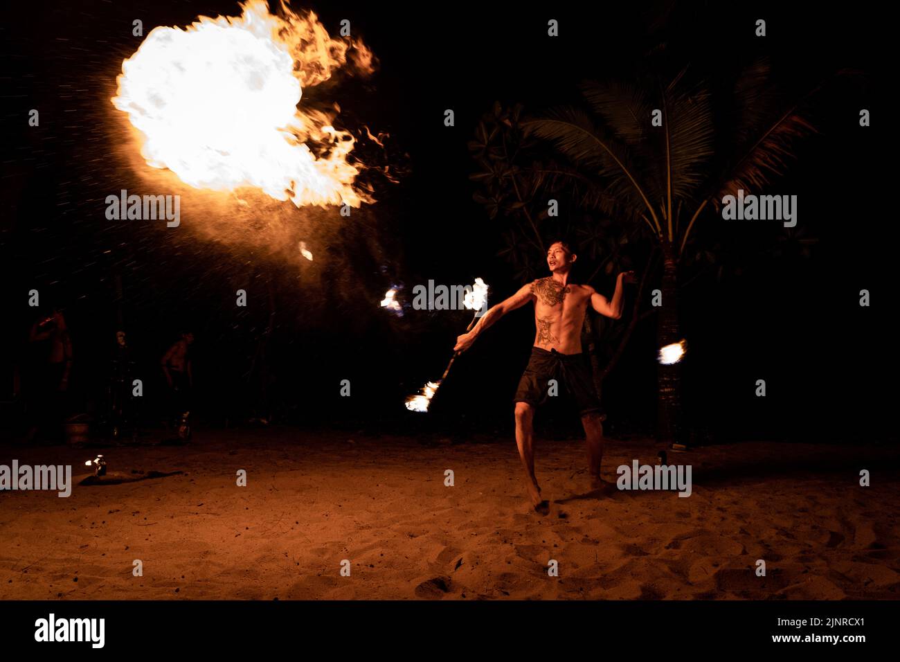 A performer spits kerosene onto a large fire at a beach in Khao Lak. To ...