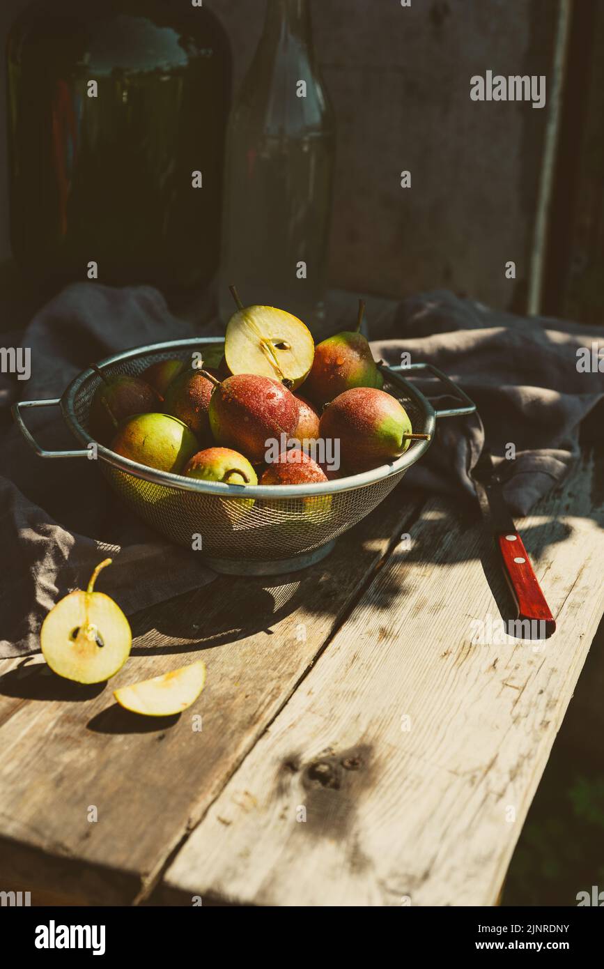 Many ripe pears in a colander on wooden garden table Stock Photo - Alamy