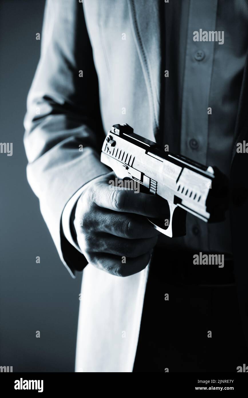 Retro secret agent with pistol revolver gun in hand in vintage crime ...
