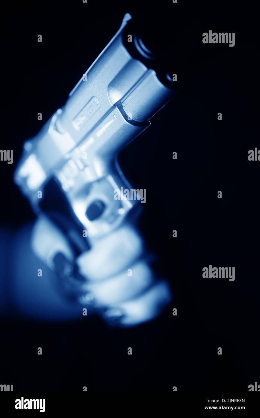 Lady spy detective with painted red nail varnish holding pistol gun at ...