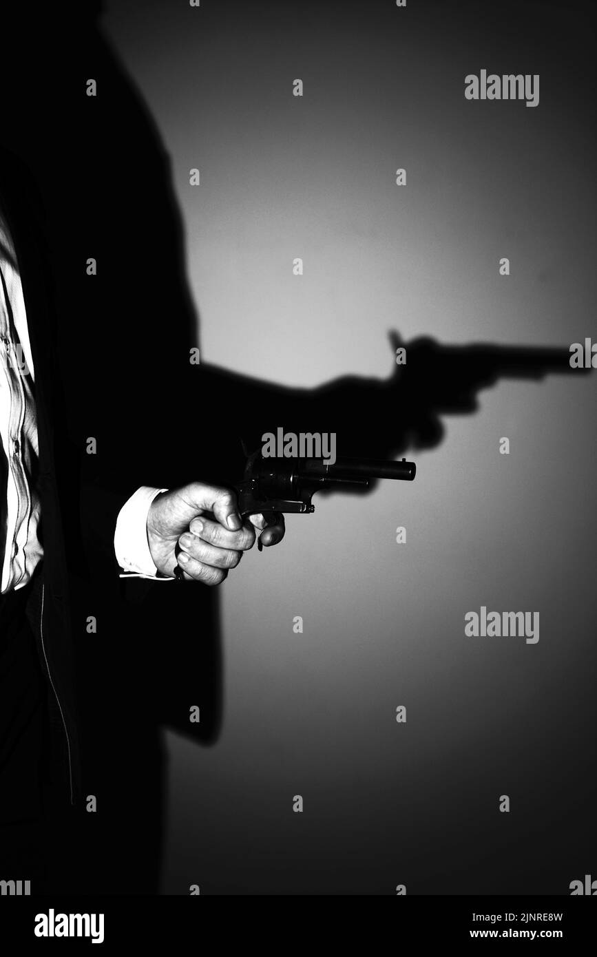 Retro secret agent with pistol revolver gun in hand in vintage crime ...