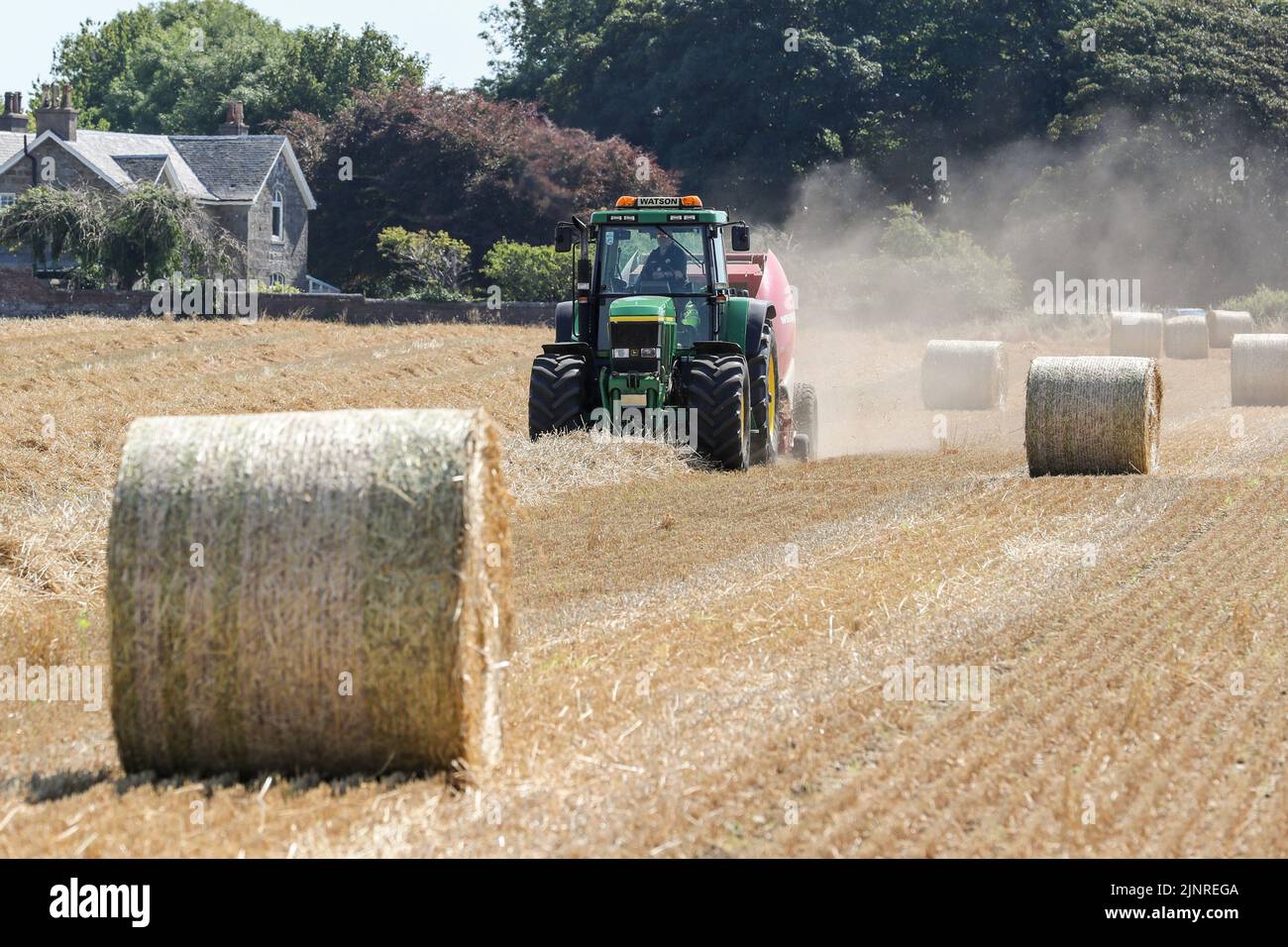Local farmer driving his John Dere tractor and baler to collect and ...