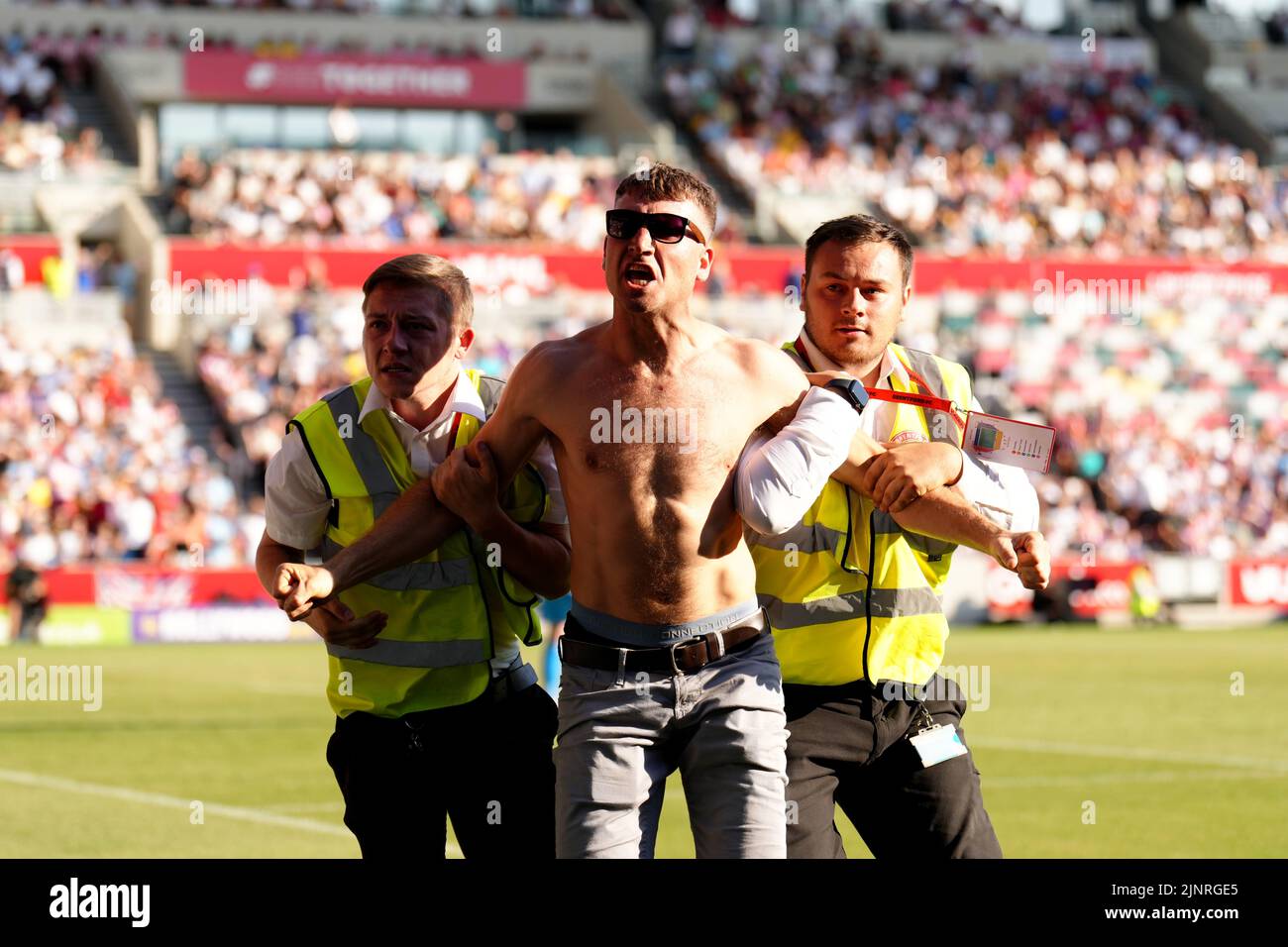 A pitch invader is taken away by security during the Premier League ...