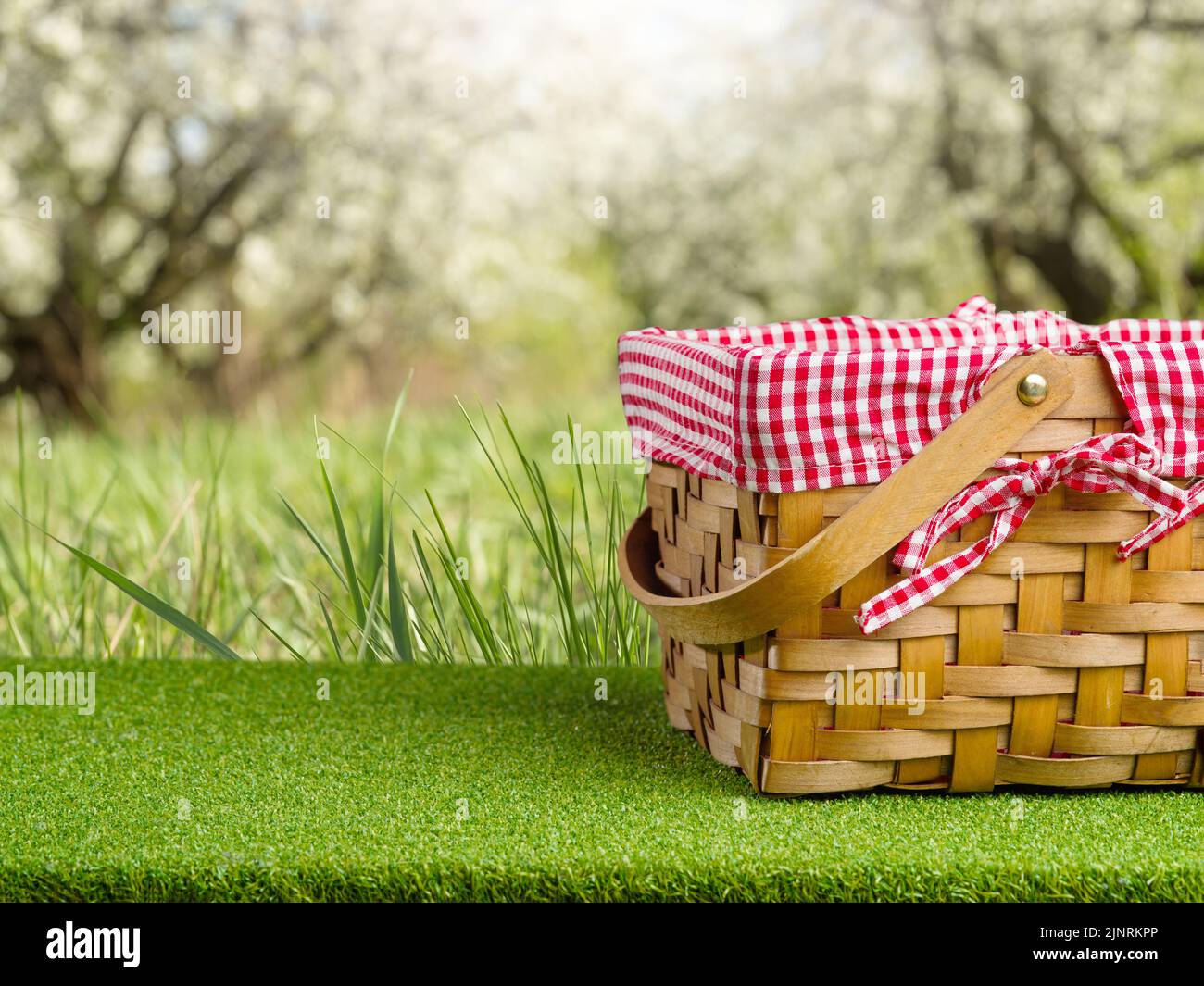 A straw picnic basket on a green lawn against the backdrop of stunning ...