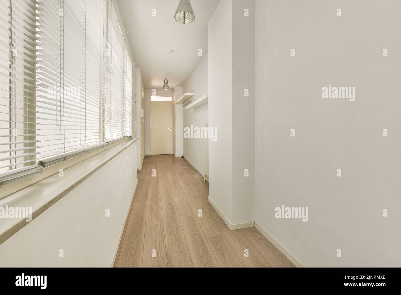 Perspective view of empty narrow hallway with white walls and wardrobe ...