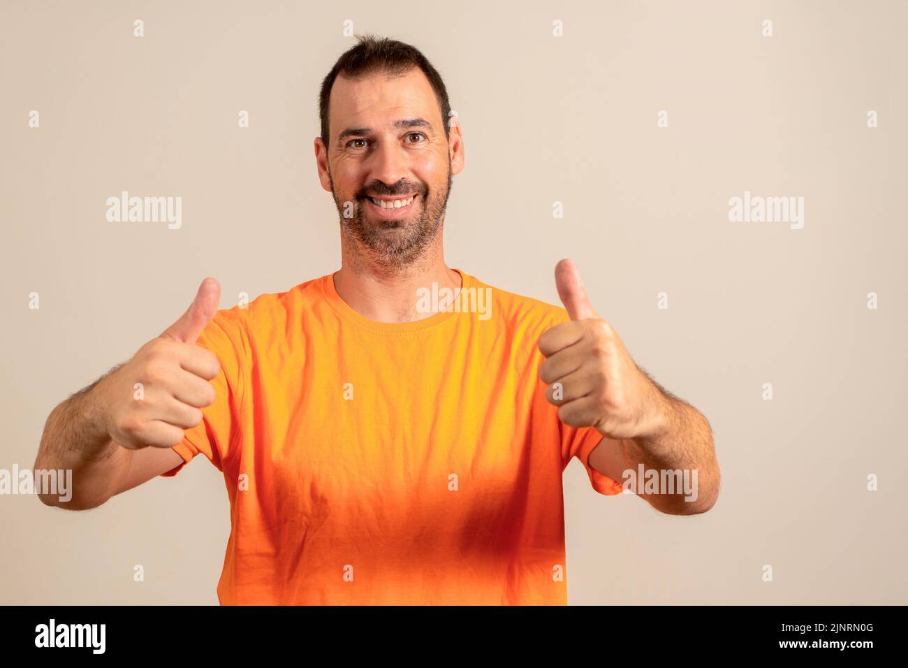 Handsome but unkempt, unshaven and out of shape man poses with thumbs ...