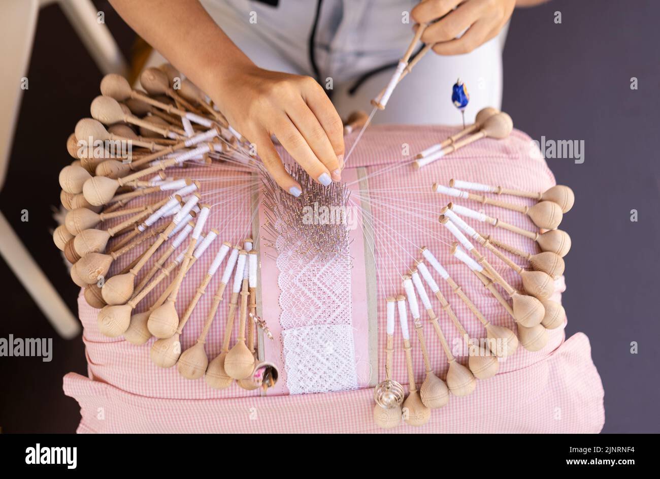 bobbin lace handcrafting. Women hands braiding threads to make a ...