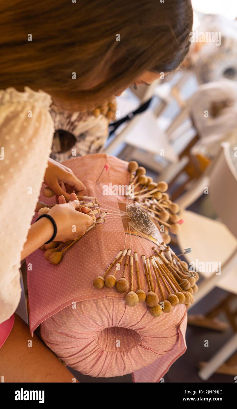 bobbin lace handcrafting. Women braiding threads to make a pattern ...