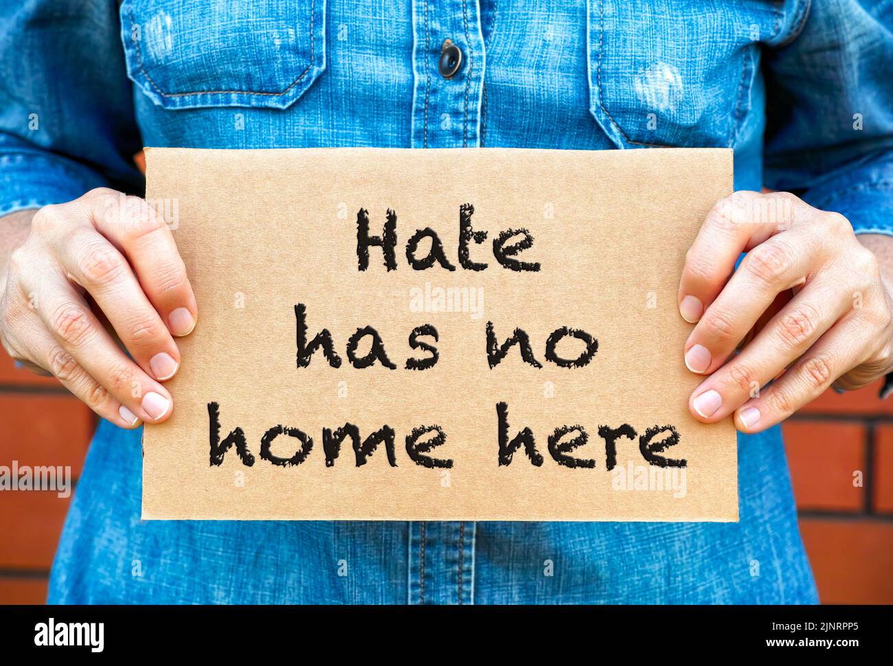 Woman hands holding piece of cardboard with words Hate Has No Home Here ...