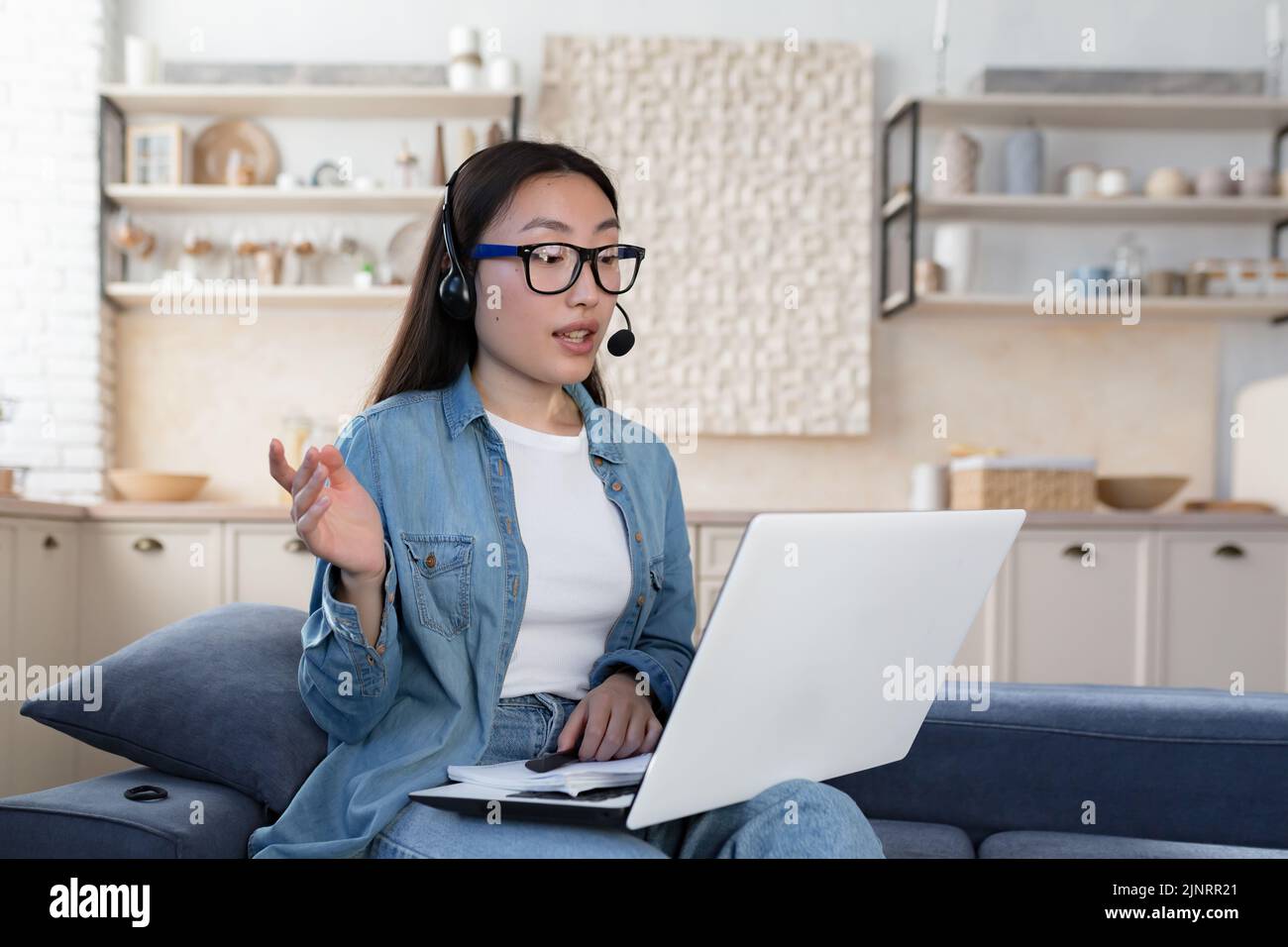 Young beautiful asian woman studying remotely sitting in living room on ...