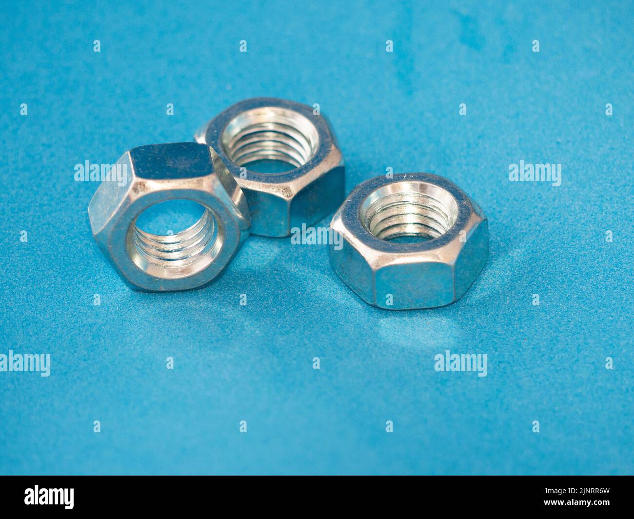 chrome-plated metal nuts on blue background. Technology concept Stock ...