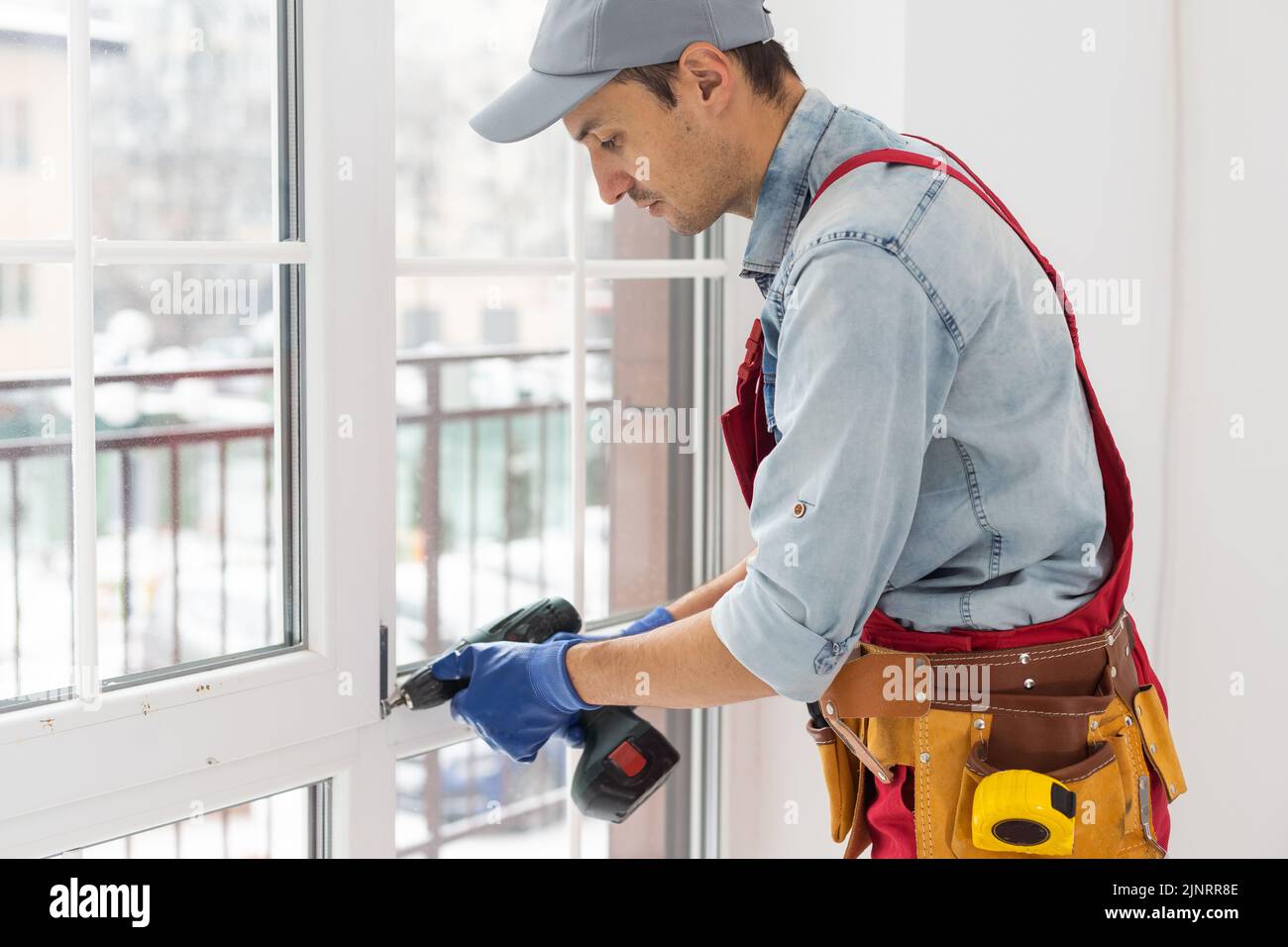 handsome young man installing bay window in a new house construction ...