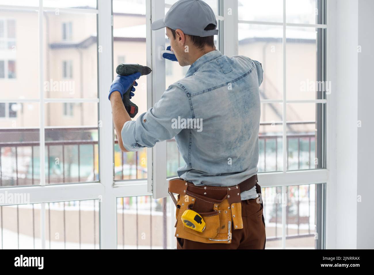handsome young man installing bay window in a new house construction ...