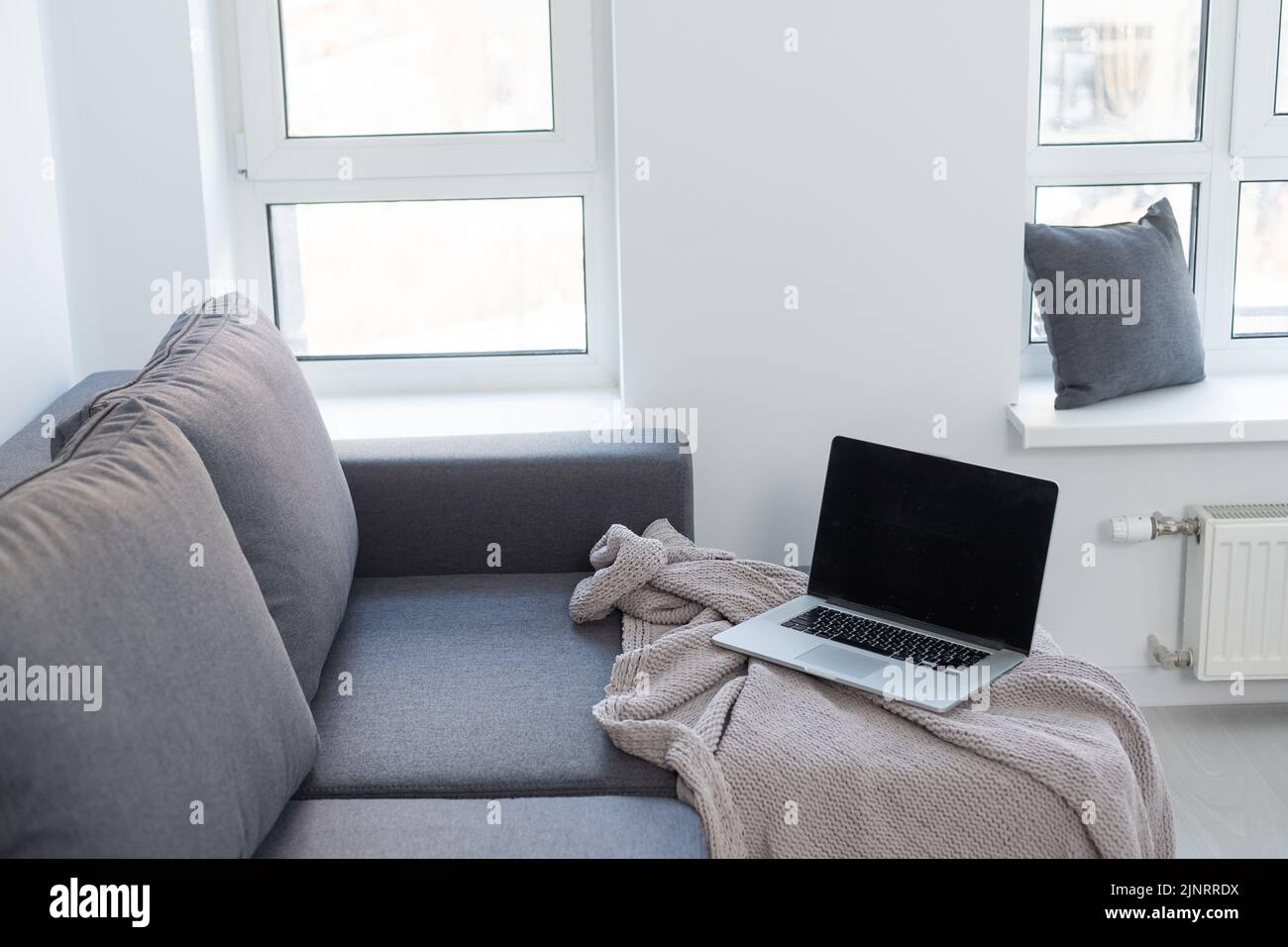 gray sofa with blanket and laptop Stock Photo - Alamy