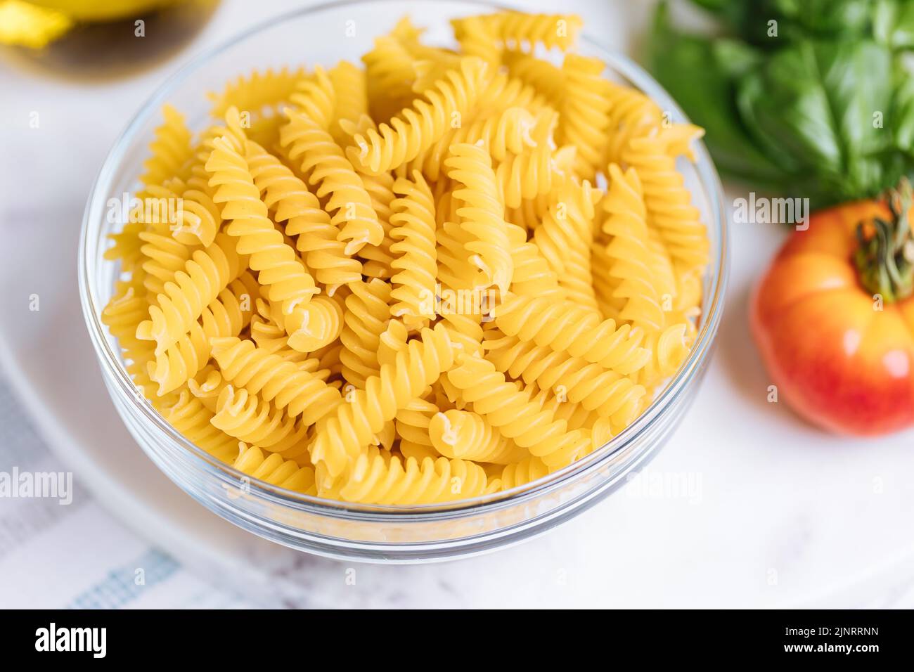 Raw Fusili pasta with other ingredients on bright background ...