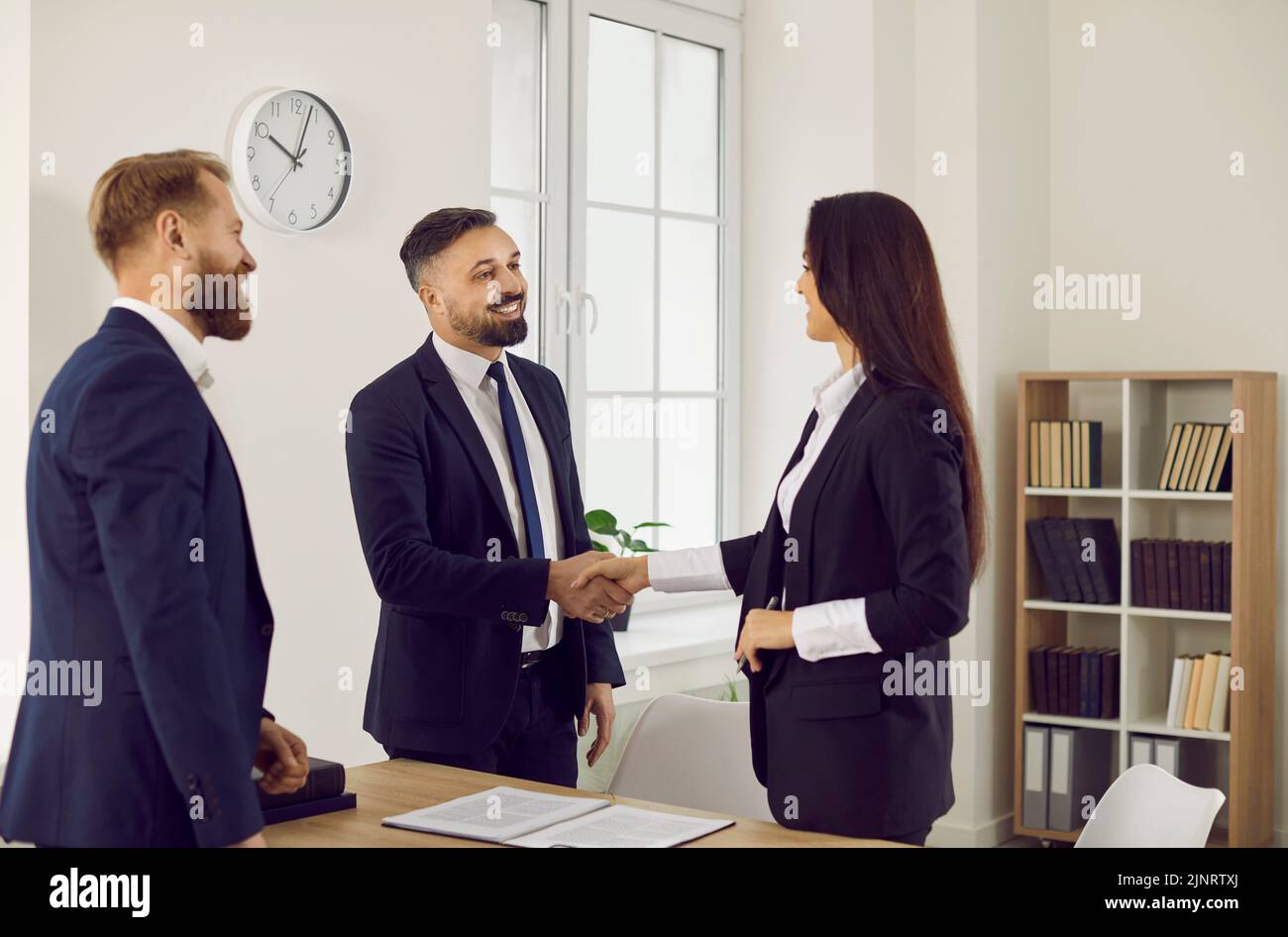 Business people end meeting by shaking hands with each other as sign of ...