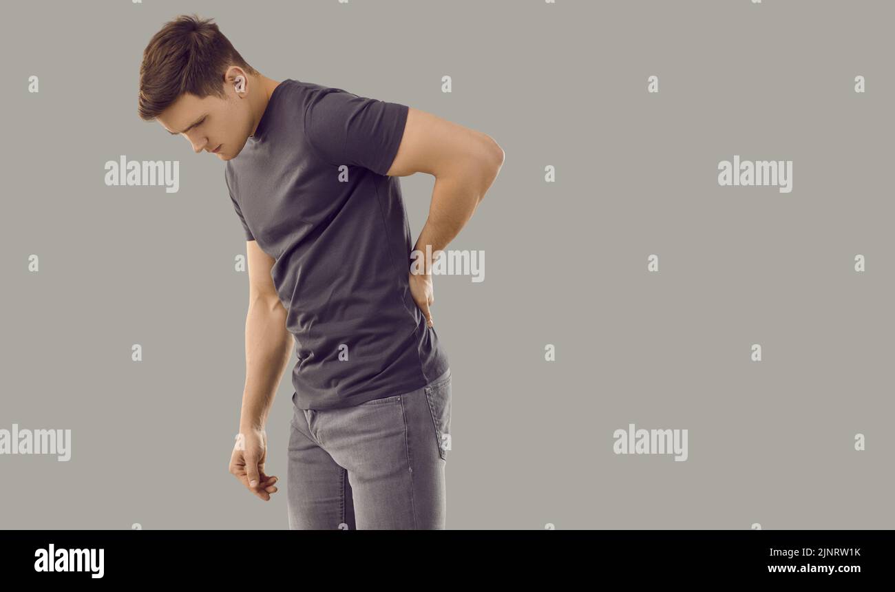 Young caucasian man holding his back because of back pain standing on ...