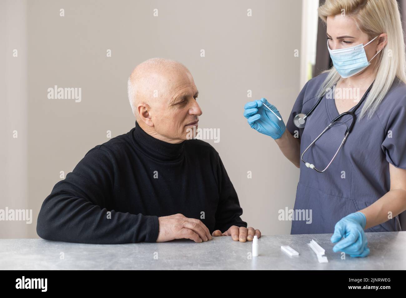 Nurse performing a coronavirus pcr test on an elderly man in his home ...