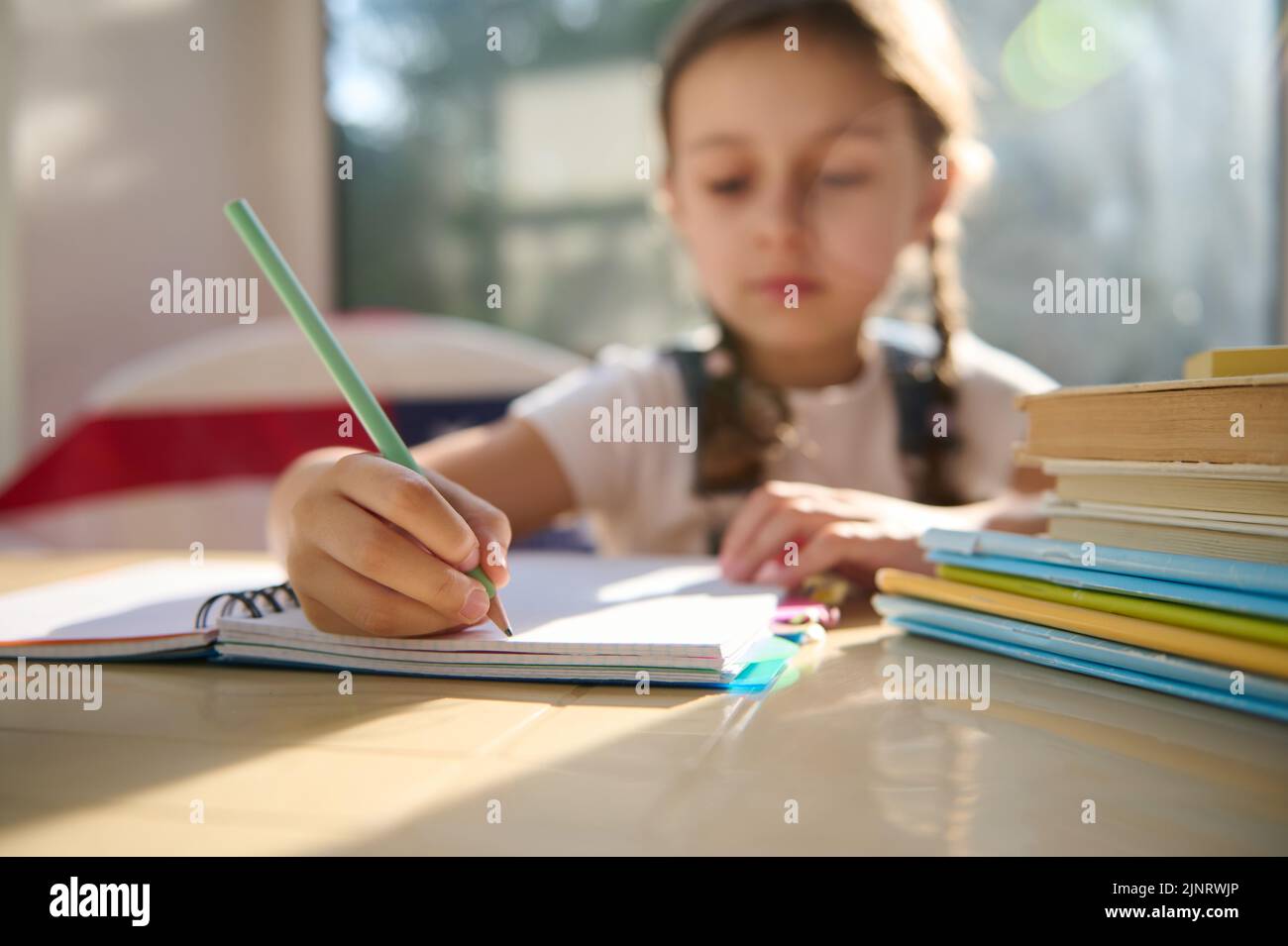 Details: Hand of schoolgirl, first grader holding pencil, making notes ...