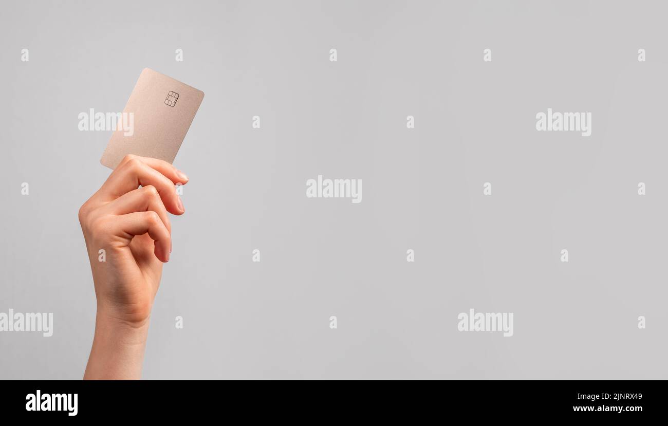Hand holding bank card with chip over gray ad background with copy ...