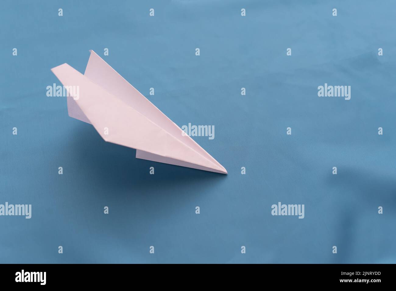White small paper airplane on a blue background Stock Photo - Alamy