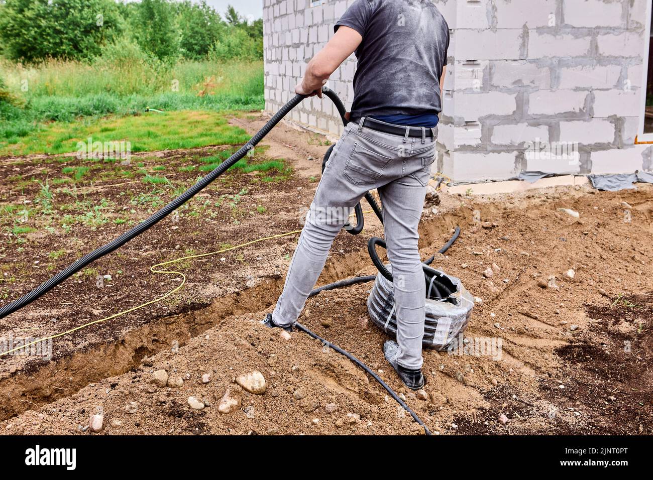 Construction worker is cabling inside trench he lays power cable at ...