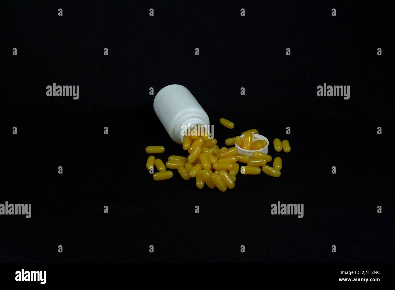 Some yellow fatty acid pills isolated on black background Stock Photo ...