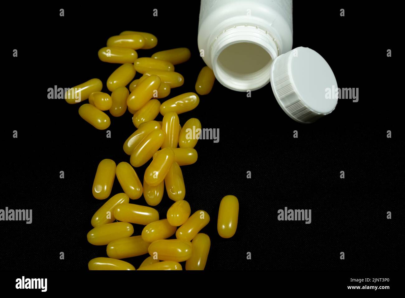 Some yellow fatty acid pills isolated on black background Stock Photo ...