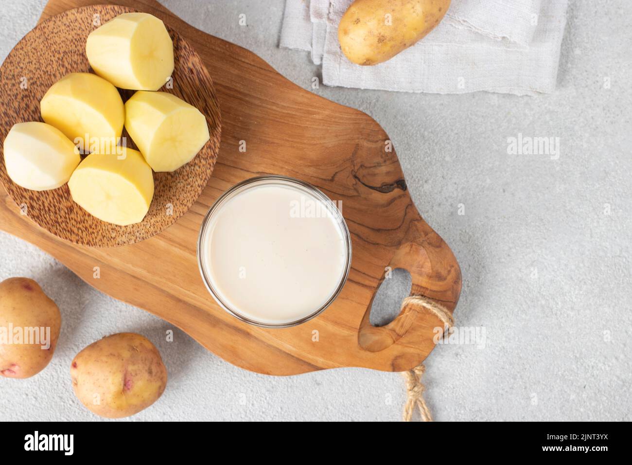 Vegan potato milk in glass and potato in plate on wooden board. Plant ...