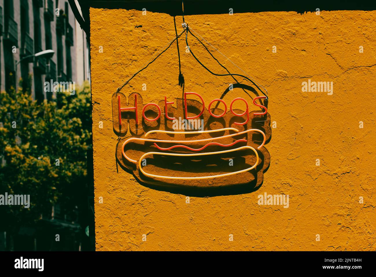 Hot dogs LED sign against yellow wall on street. Fast food bistro, cafe ...