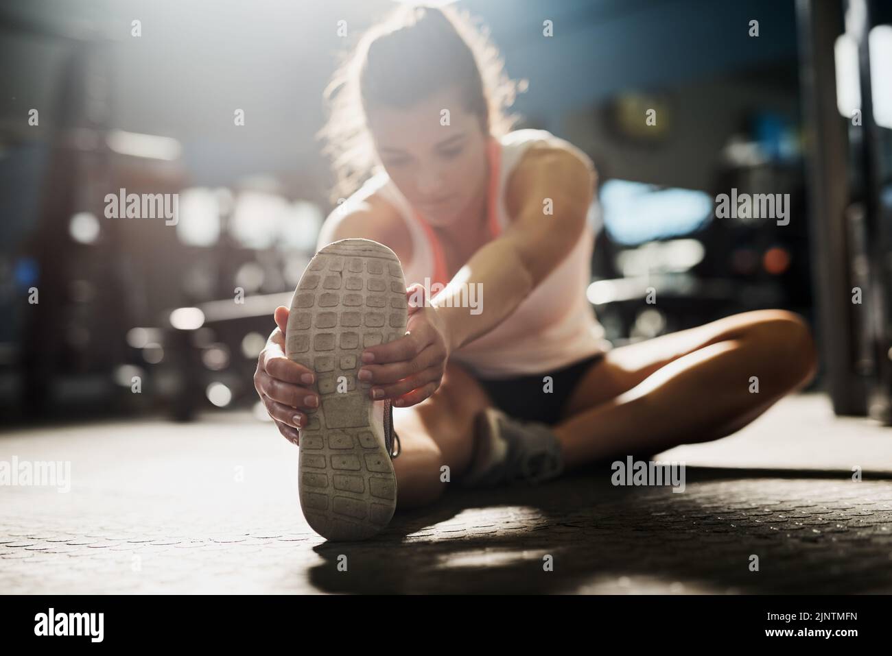 Make today your someday. a young woman doing stretch exercises at the ...