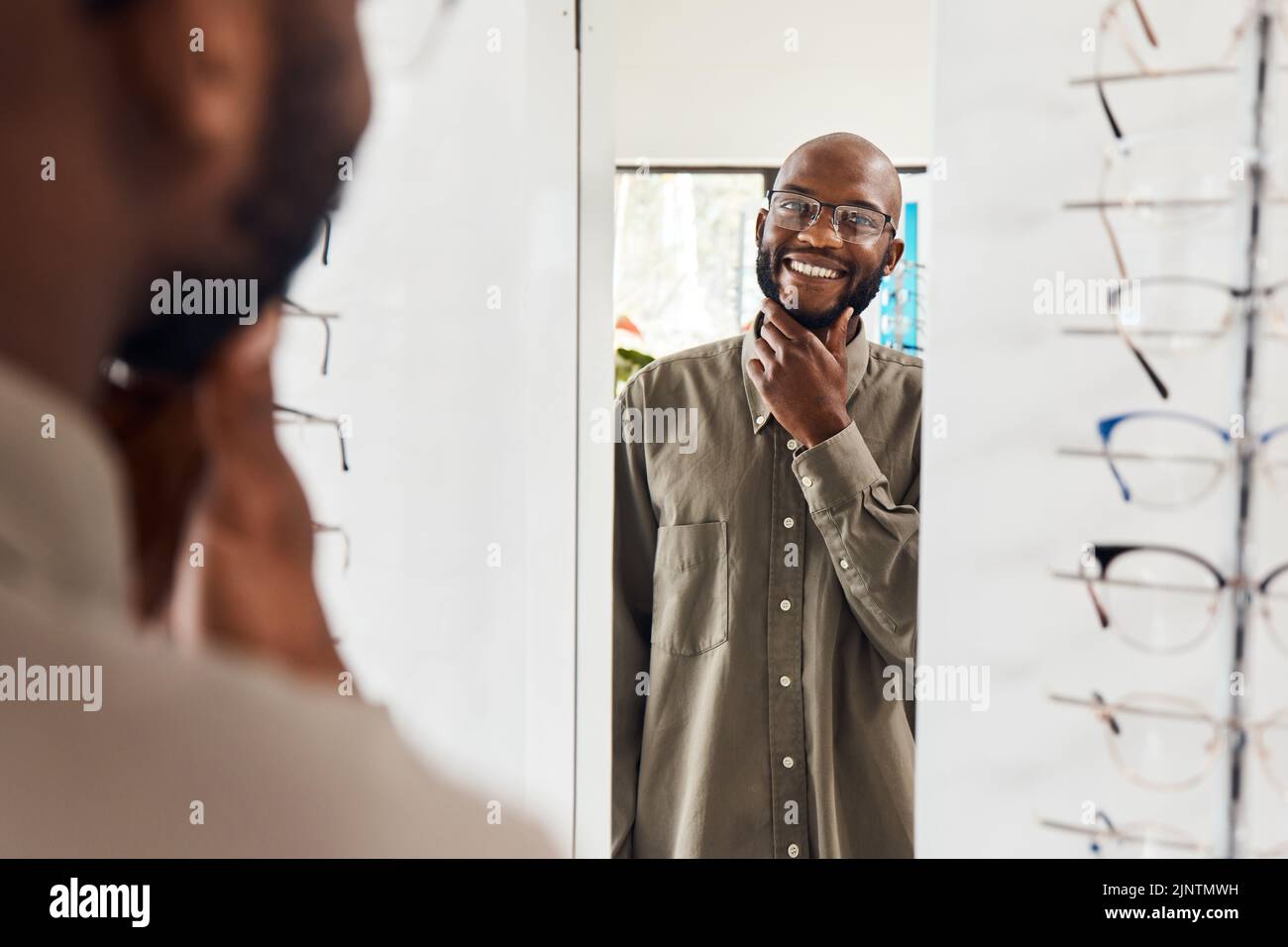 Customer trying on glasses at an optometrist, smiling and looking ...