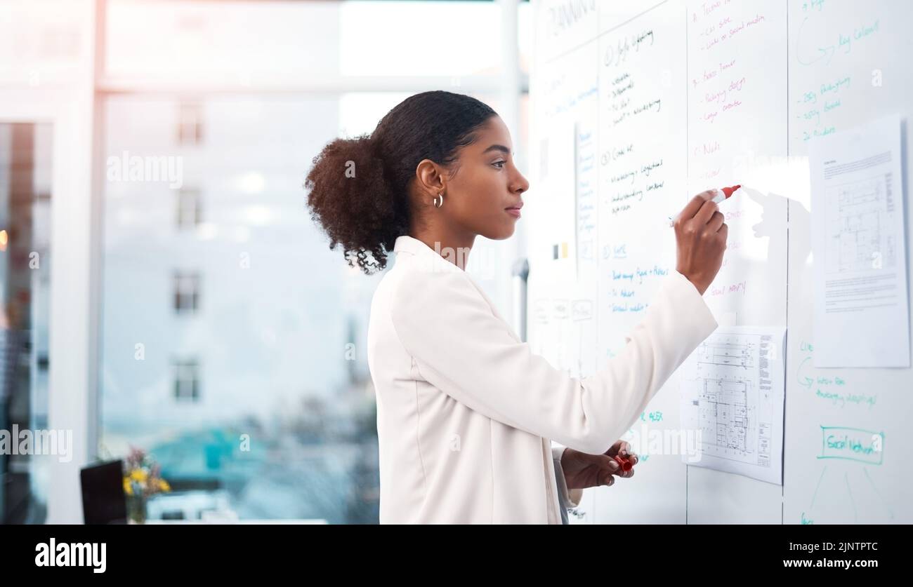 Businesswoman planning marketing strategy on a whiteboard in modern ...
