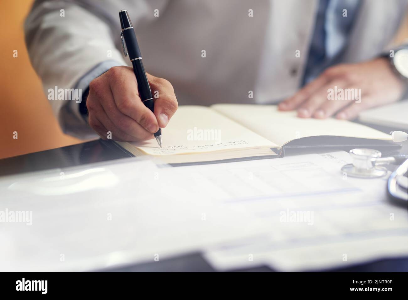 Checking his schedule. an unrecognizable male doctor writing in his ...