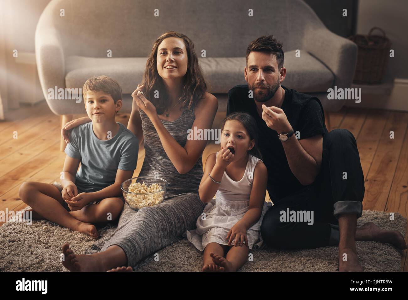 Turning their living room into a cinema. a young family relaxing on the ...