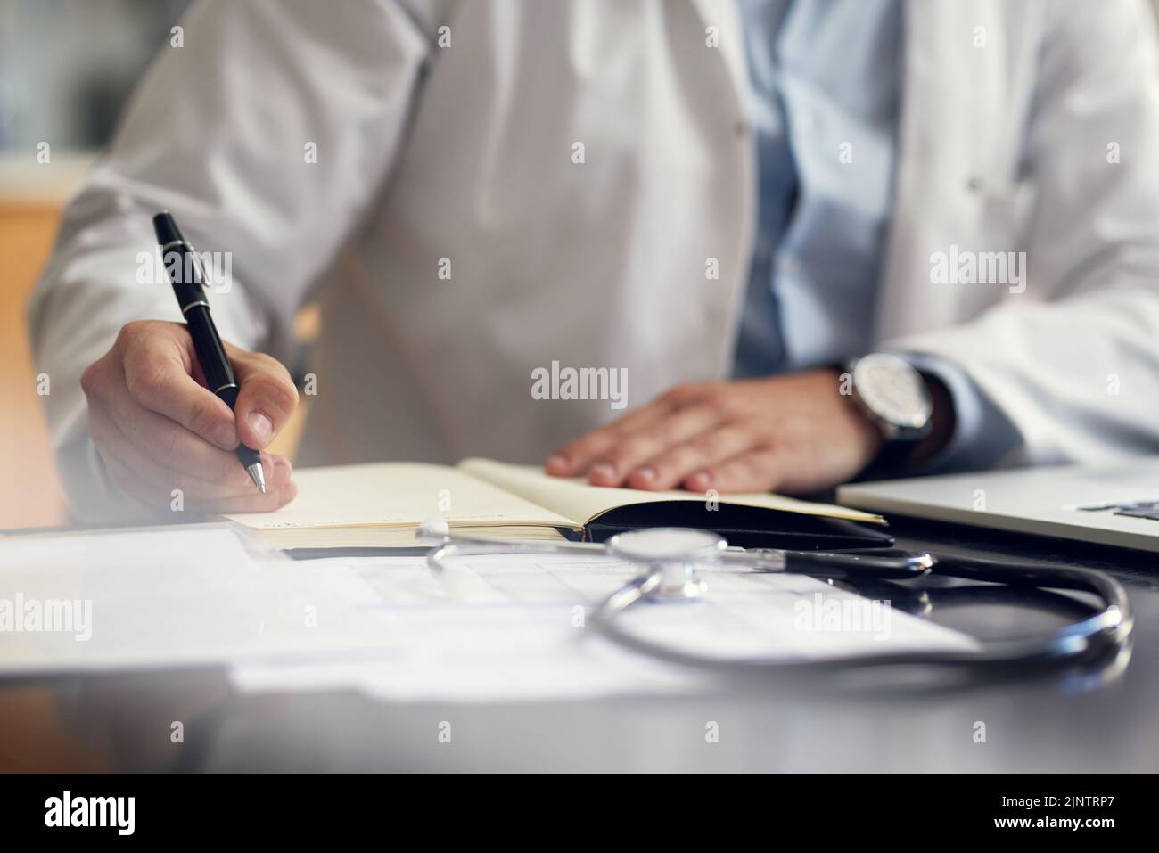 Writing down notes for every patient. an unrecognizable male doctor ...