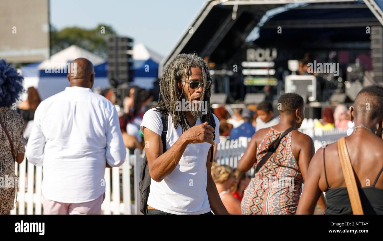 A black male with greying dreadlocks dances at an open air, outdoor ...