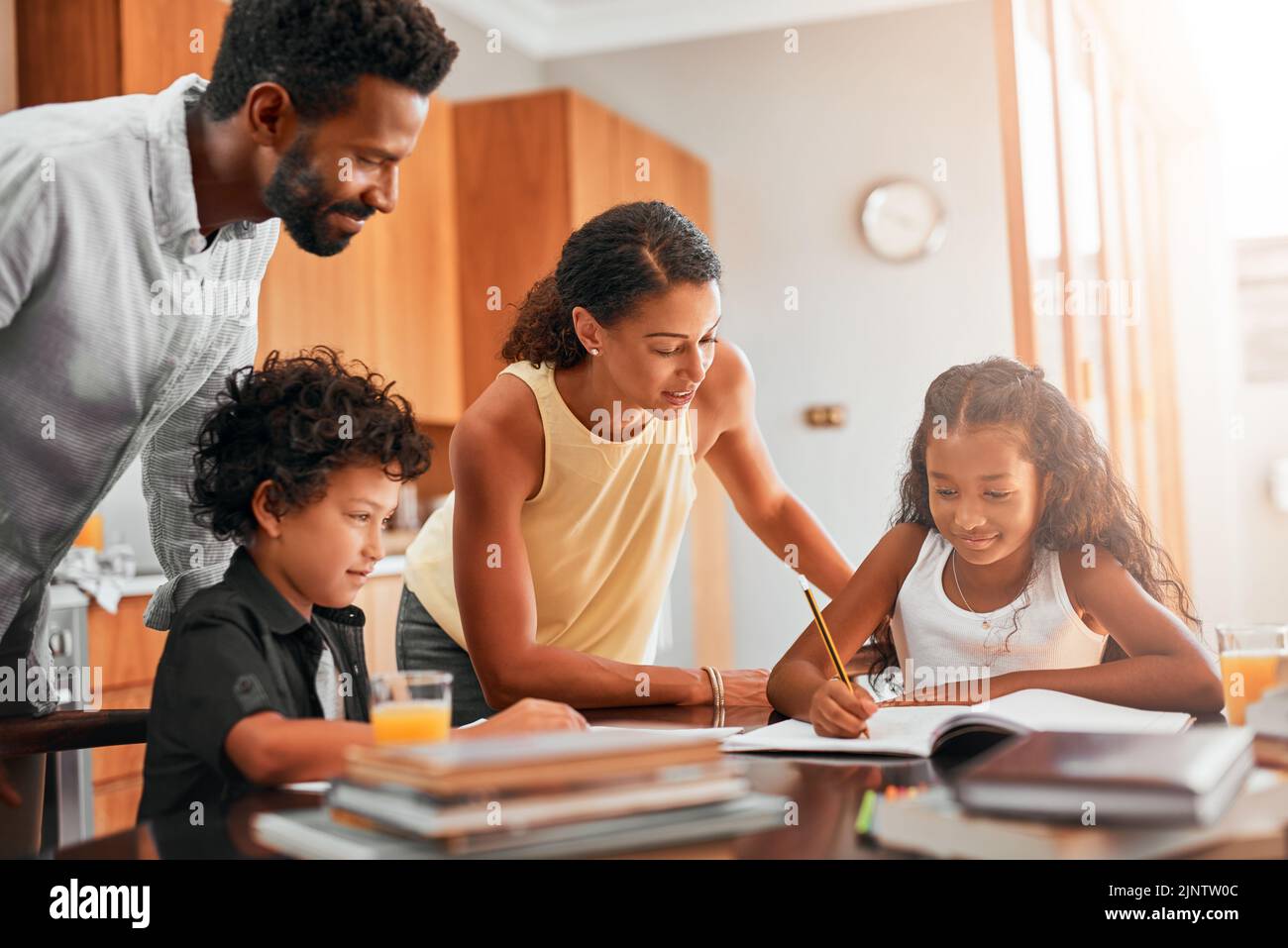 Getting homework done before playtime. parents helping their two children with their homework ...